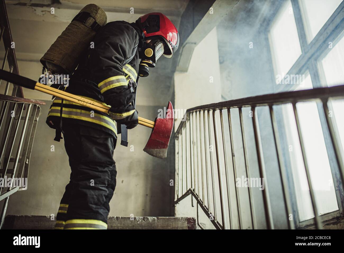 young fireman in action, stand in landing, go to fight with fire ...