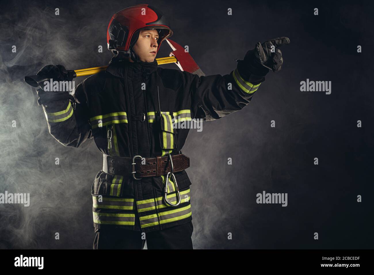 young caucasian fireman show at fire, serious male in uniform gives a ...