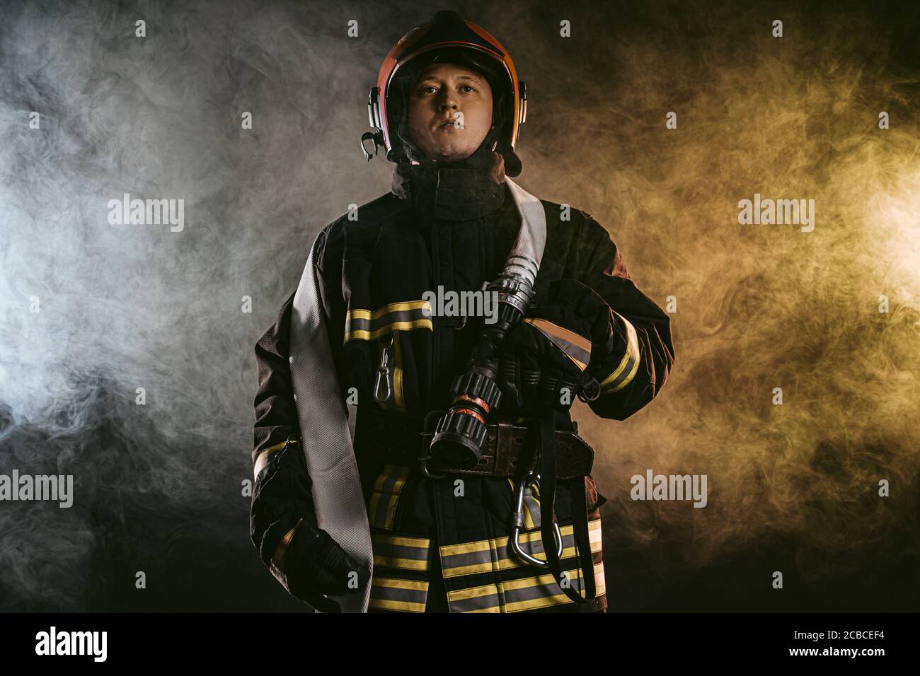 portrait of confident handsome fireman in helmet and uniform, serious ...