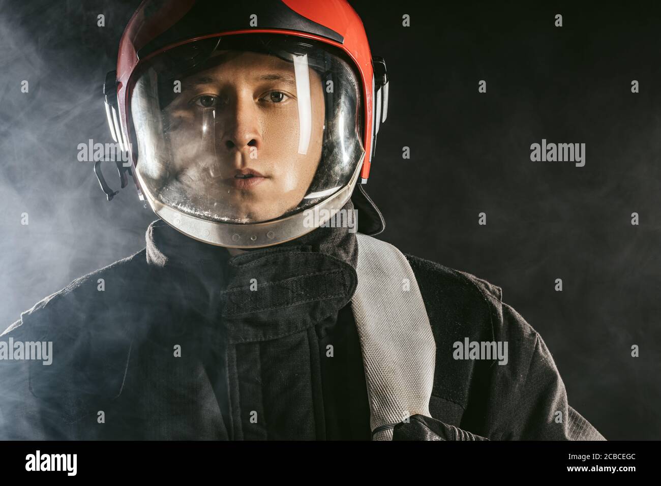 portrait of confident handsome fireman in helmet and uniform, serious ...