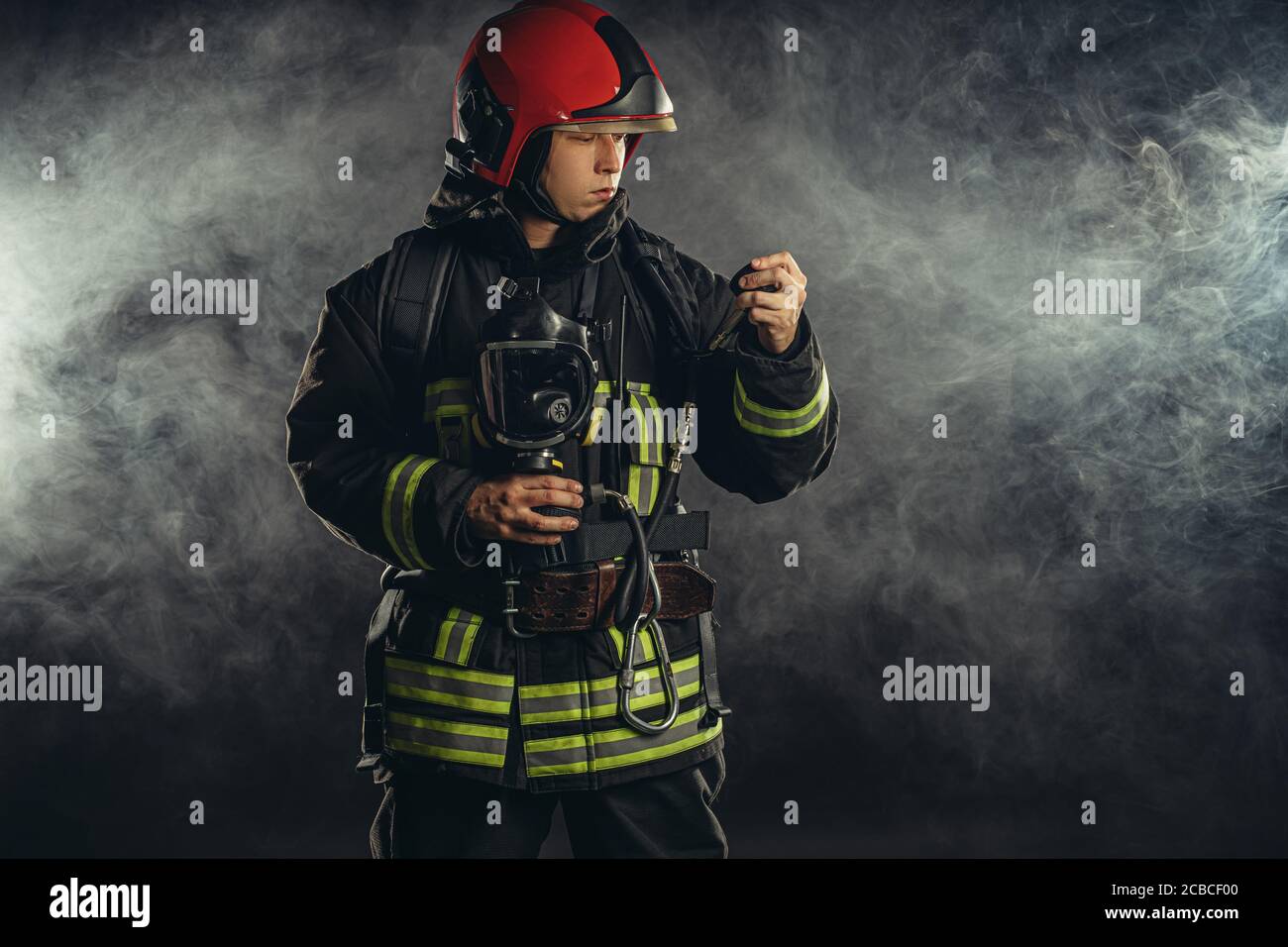 brave firefighter extinguishing fire in smoke, using special equipment ...