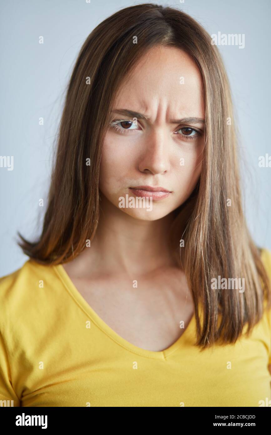 frowning serious girl isn't satisfied with hernface, close up portrait ...