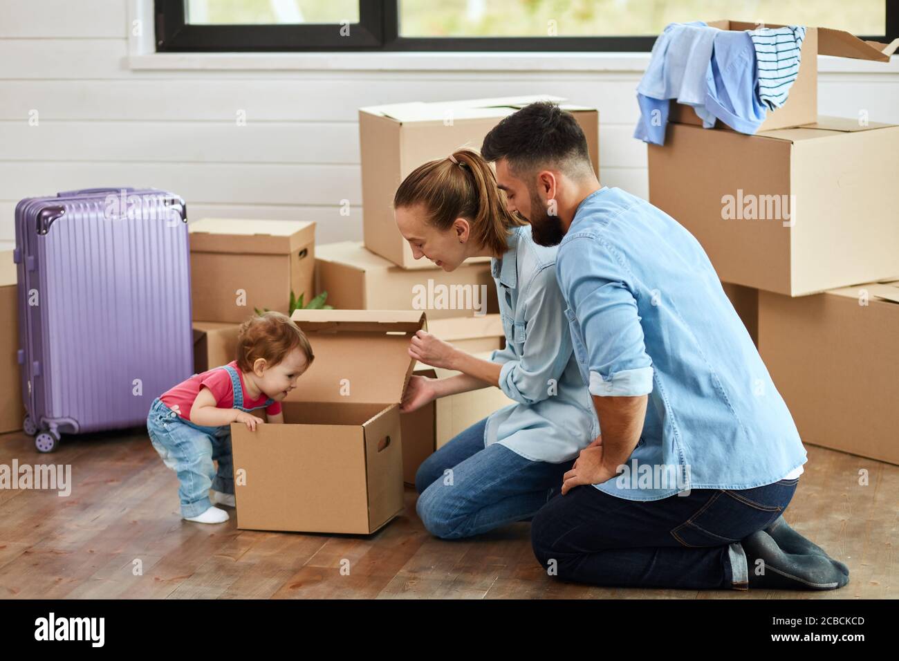Couple wear blue shirt peek box which carries kid wear denim overalls ...