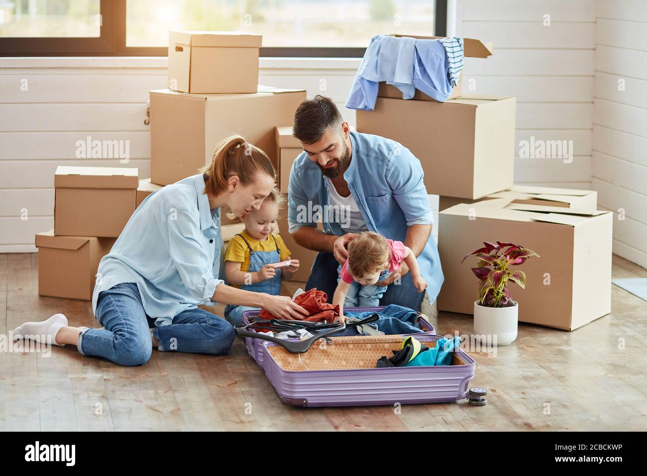 Happy caucasian family sit on floor, unpack suitcase in new house ...