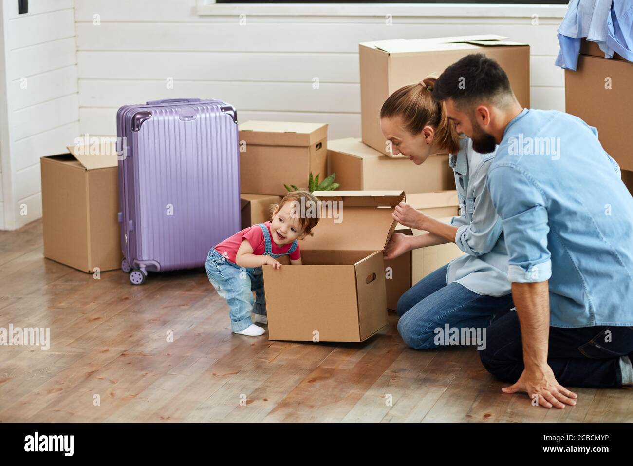 Couple wear blue shirt peek box which carries kid wear denim overalls ...