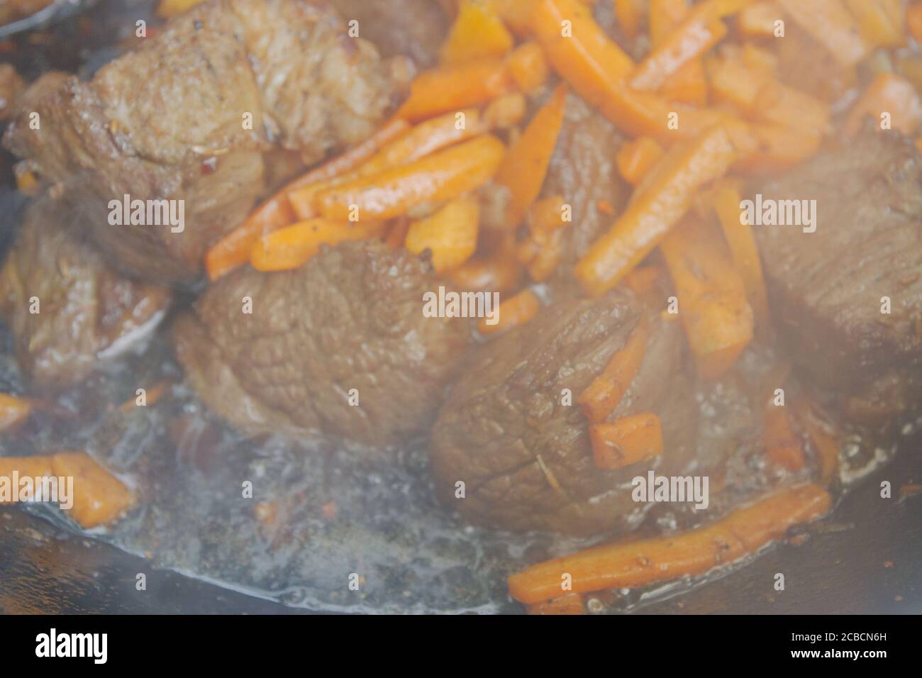 Cooking pilaf in a cauldron on the grill outside in the summer Stock ...