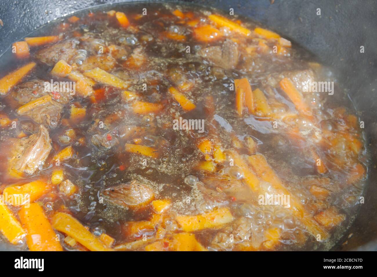 Cooking pilaf in a cauldron on the grill outside in the summer Stock ...