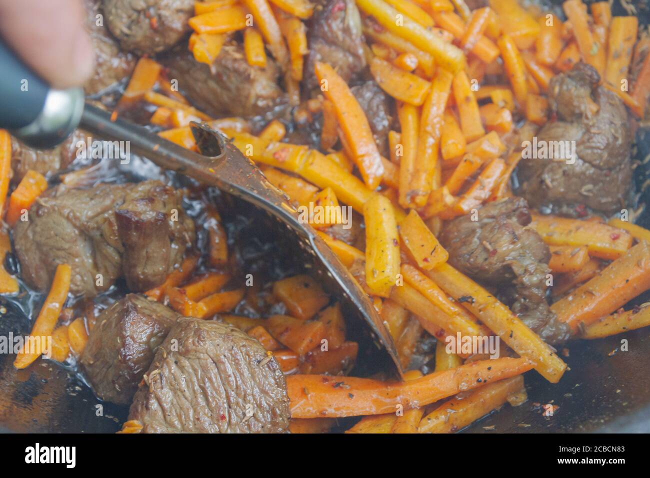 Cooking pilaf in a cauldron on the grill outside in the summer Stock ...