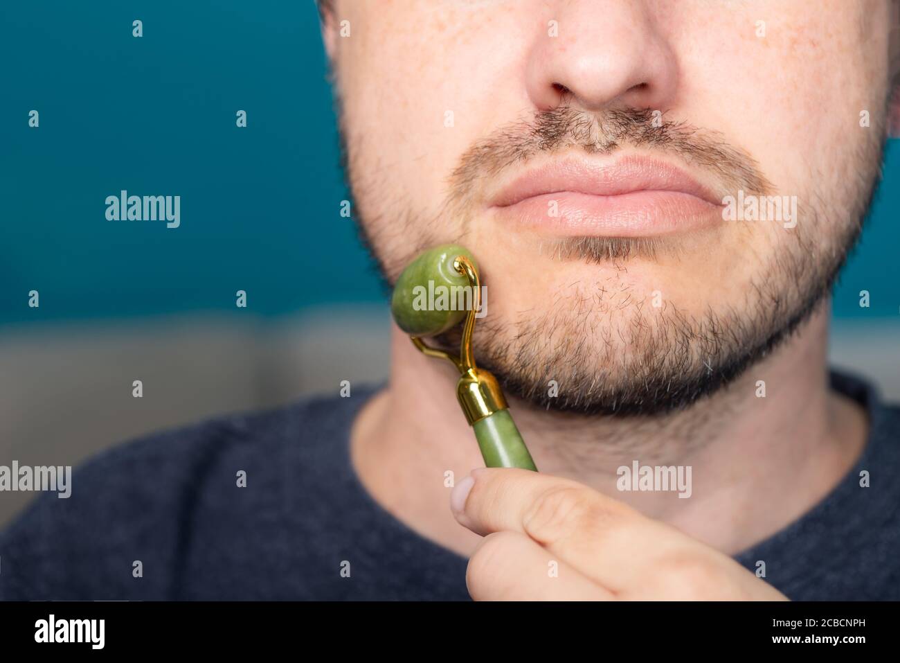 Bearded man is using jade face roller Stock Photo - Alamy