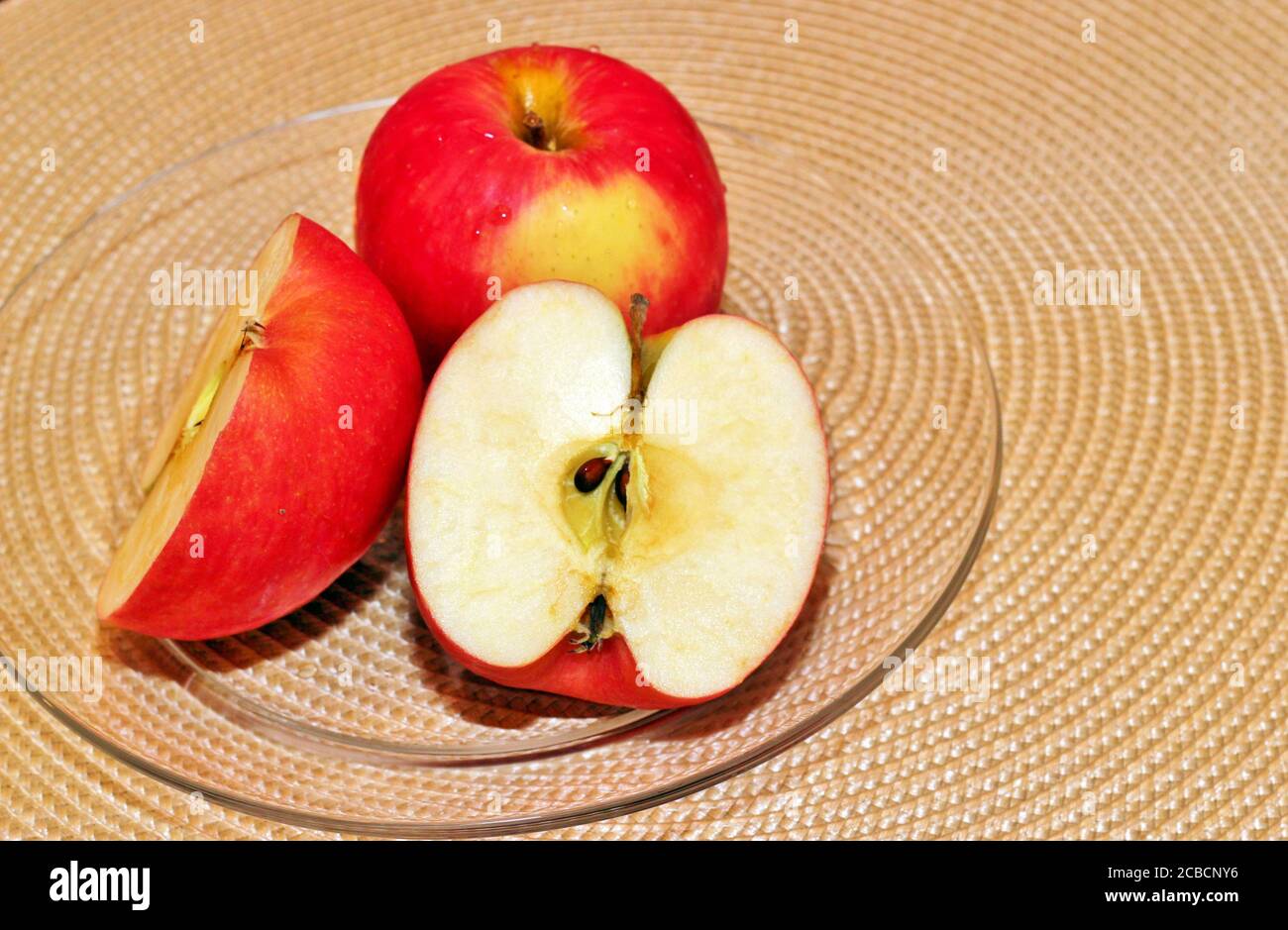 Apples on a plate. One whole, one cut in half Stock Photo - Alamy