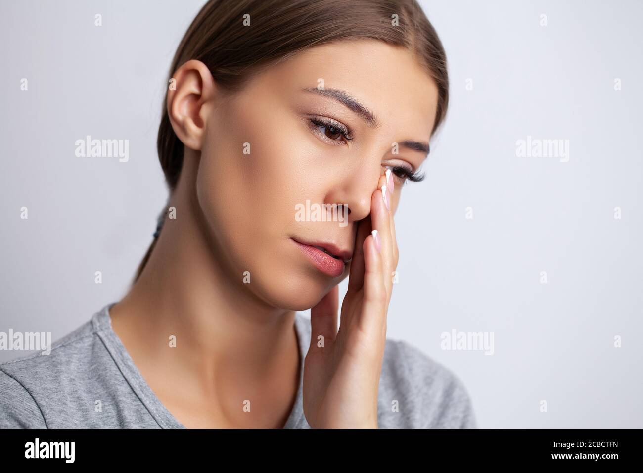 A young woman feels severe pain on her face touching the pain area with ...