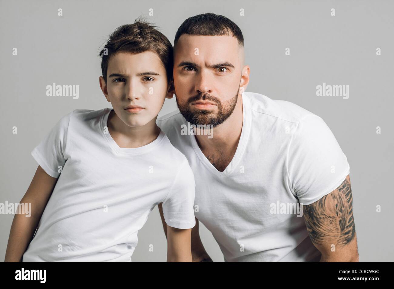 Puzzled daddy and his son with clueless expression looking at the ...