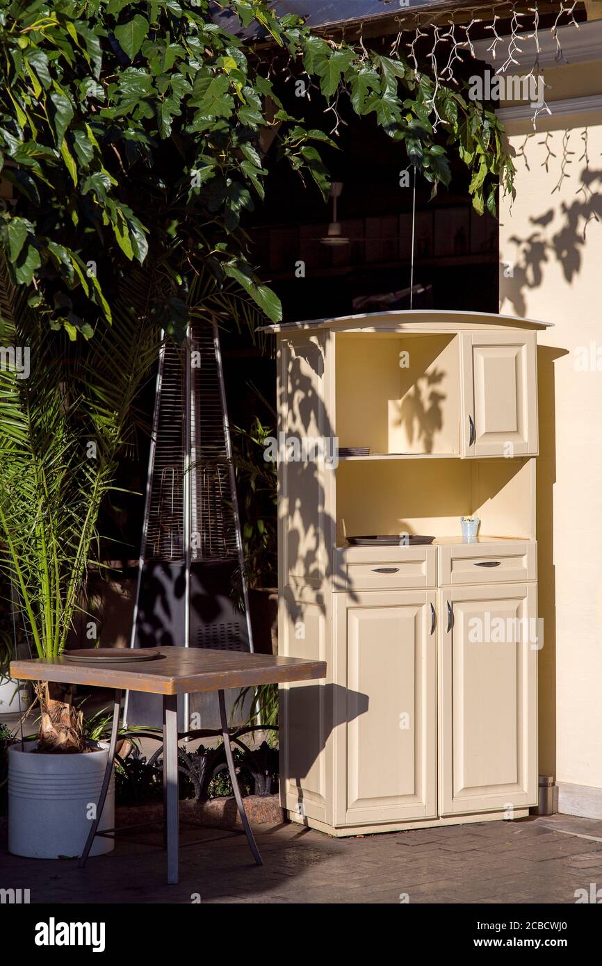 Kitchen cabinet with a table outside under a tree with a pot for plants ...