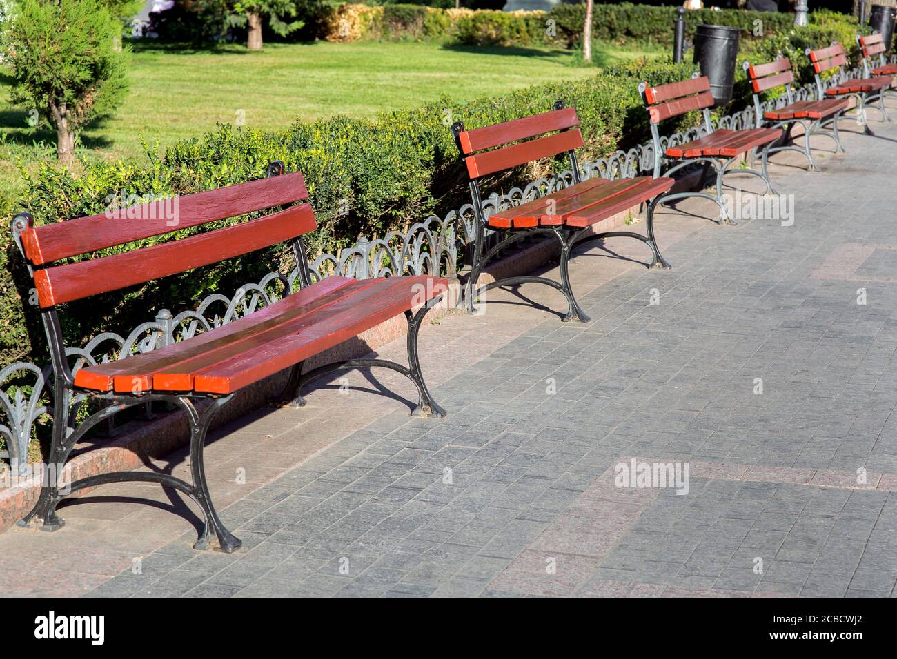 a row of benches on the pedestrian sidewalk in the park area of the ...