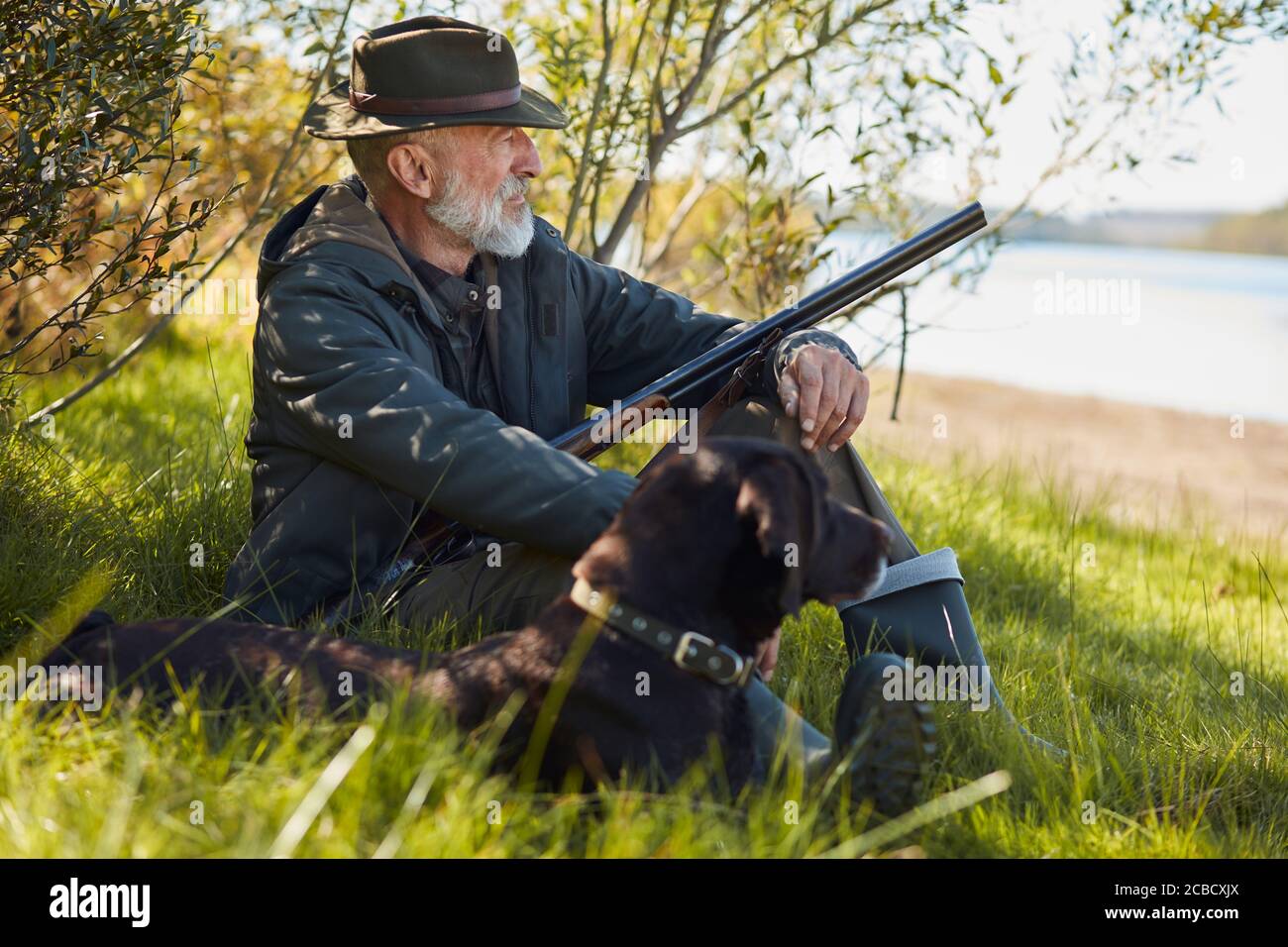 Hunter male with gun sit with faithful dog during hunting. Forest ...