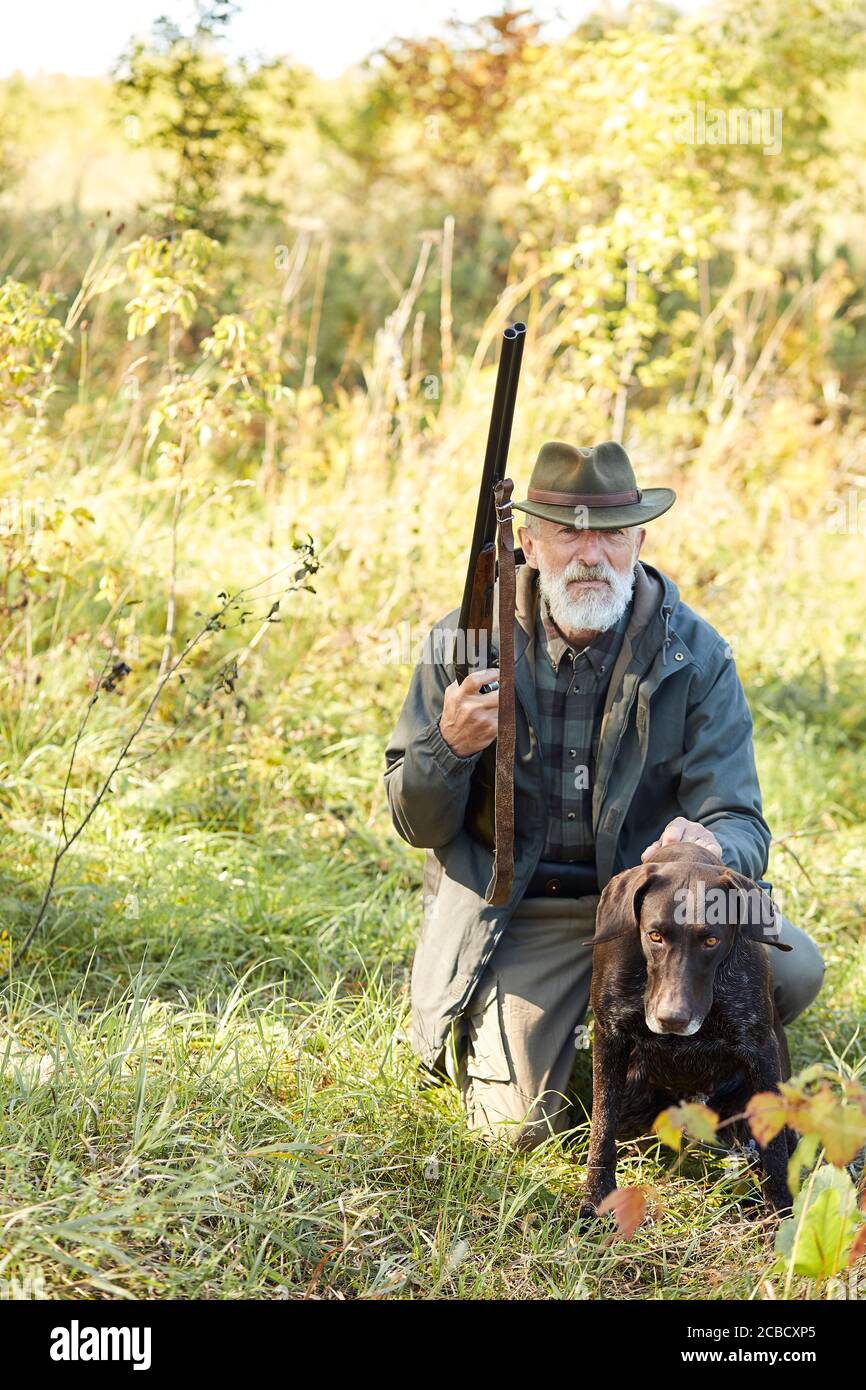 Senior hunter and his dog in forest, look for prey, hunting on wild ...