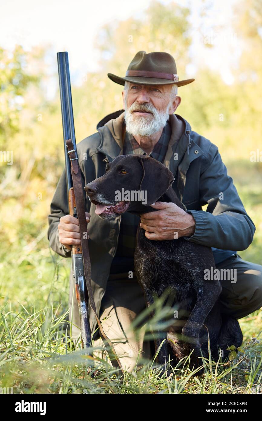 Senior hunter and his dog in forest, look for prey, hunting on wild ...