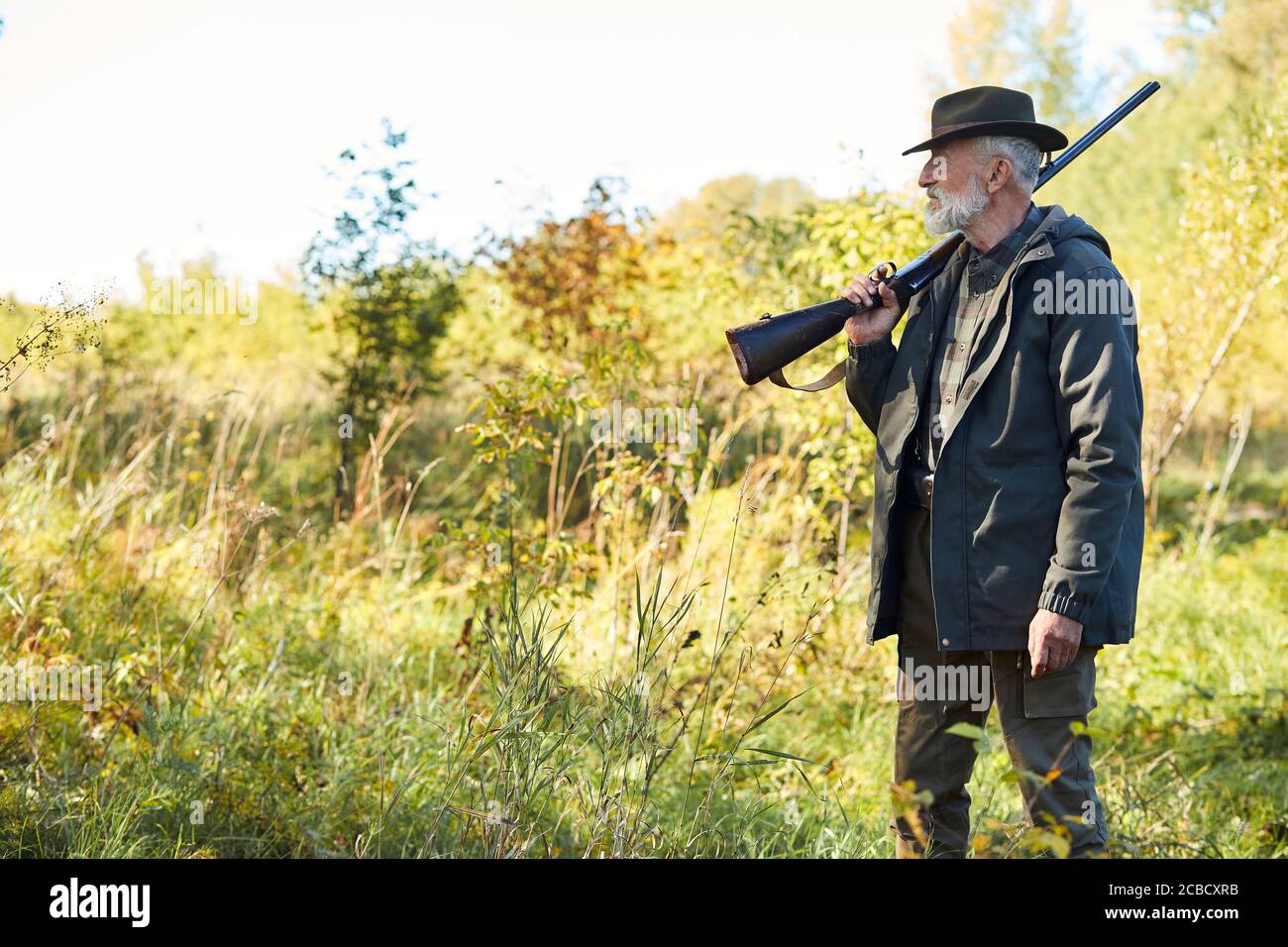 Older man stand looking for new trophy in forest, wearing hunting ...