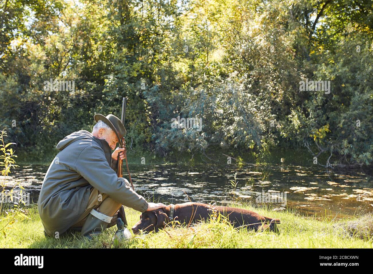 Have rest before hunting. Hunter man on lake, holding rifle Stock Photo ...