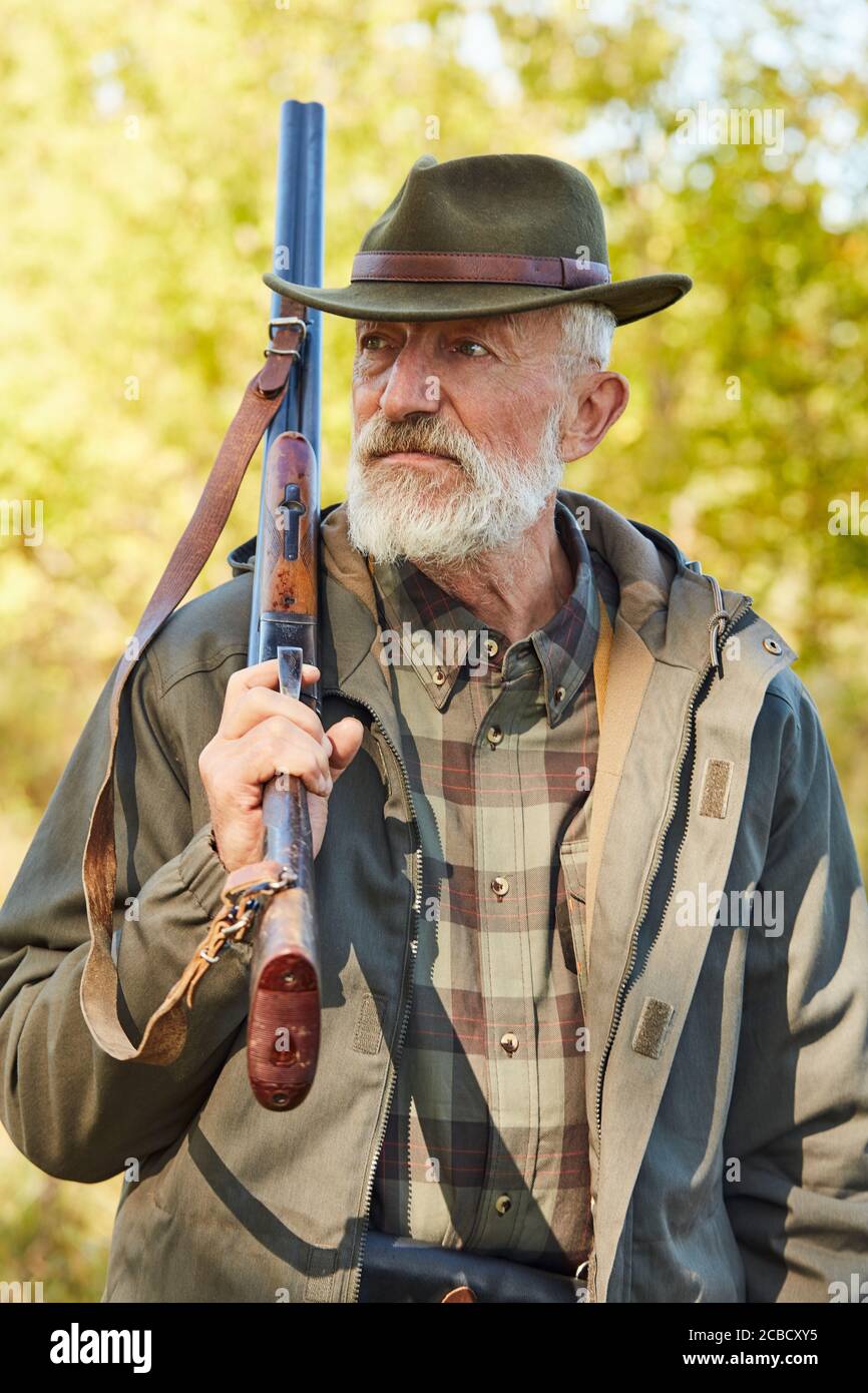 Senior caucasian man with hunting gun looking away, man with grey beard ...