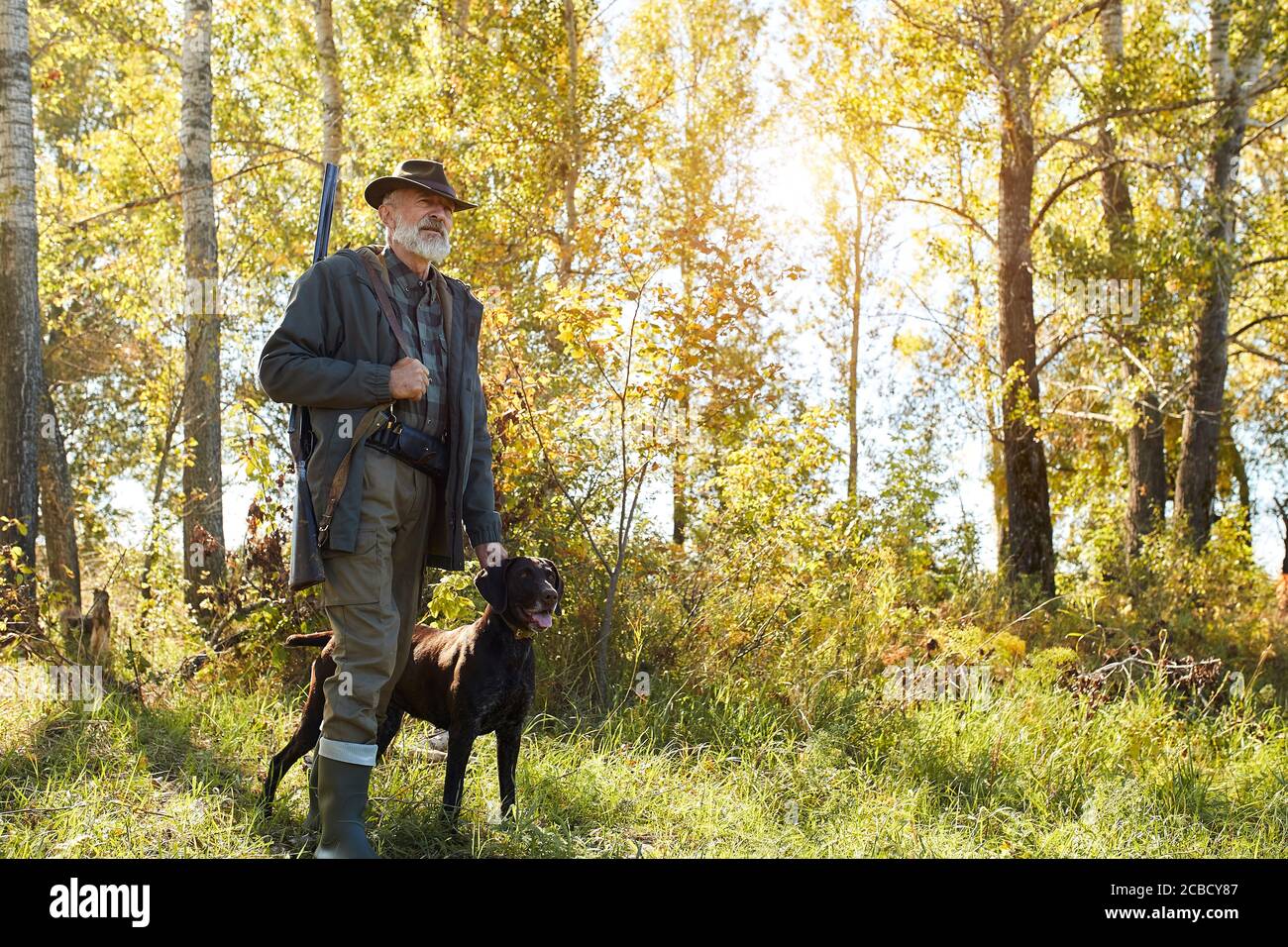 Senior hunter and his dog in forest, look for prey, hunting on wild ...