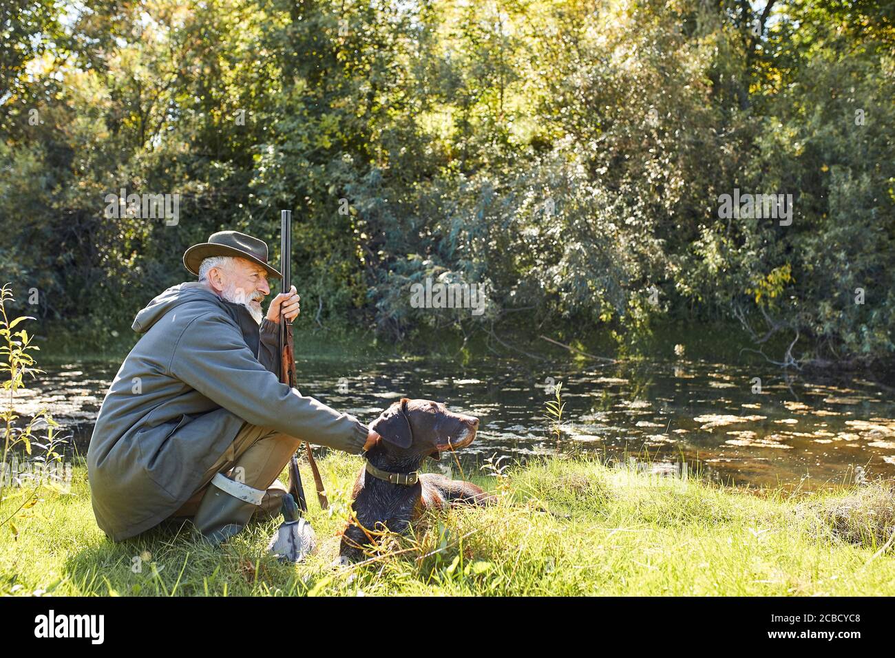 Have rest before hunting. Hunter man on lake, holding rifle Stock Photo ...