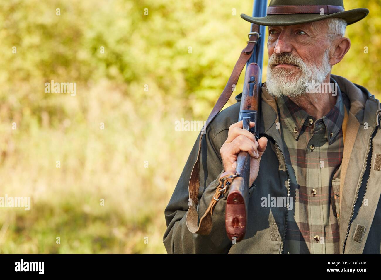 Senior caucasian man with hunting gun looking away, man with grey beard ...