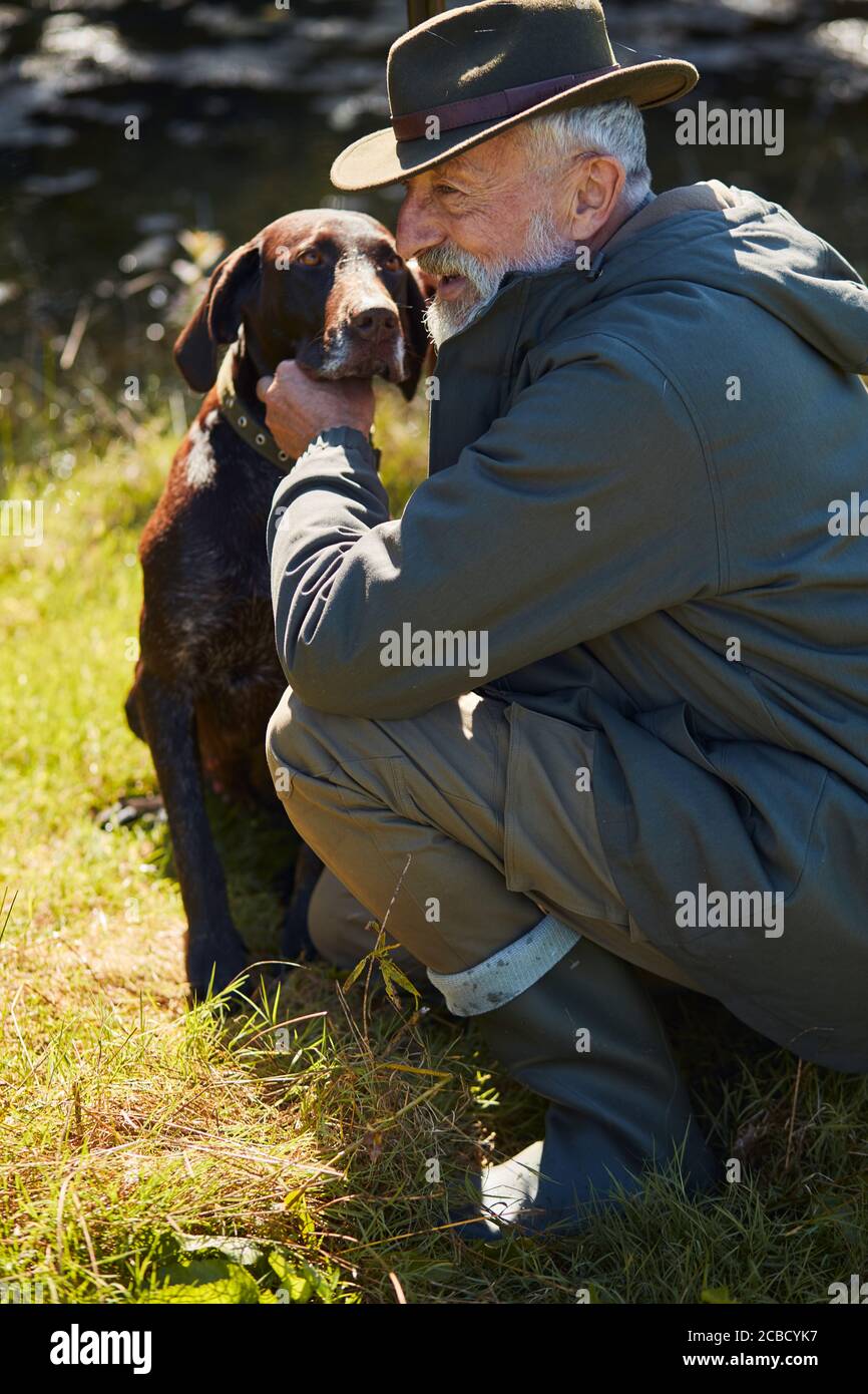 Docile dog with his owner sit on grass. side view on man Stock Photo ...