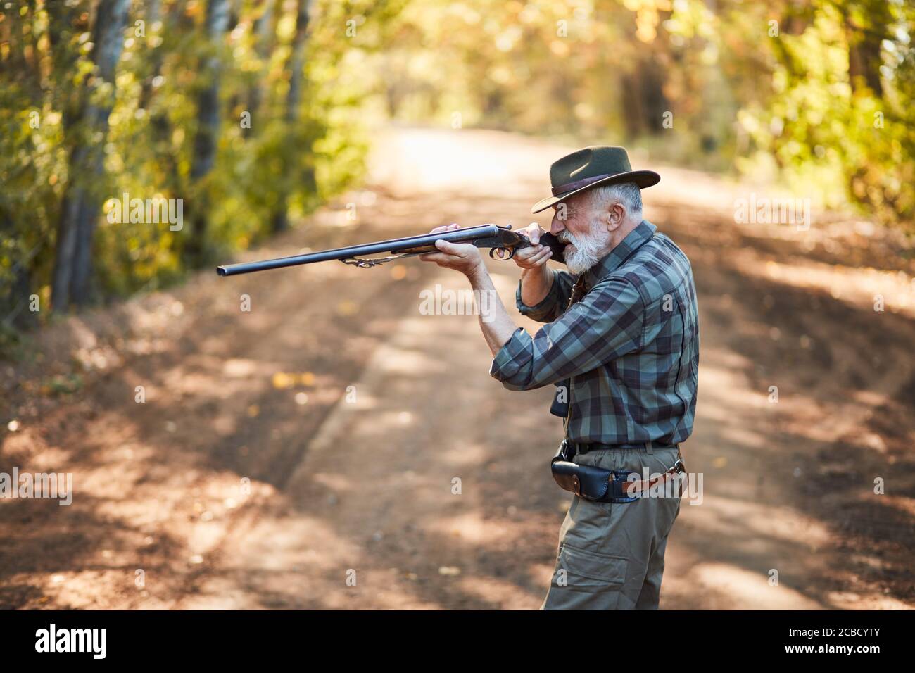 Side view on senior hunter man aims at trophy bird in autumn sunny ...