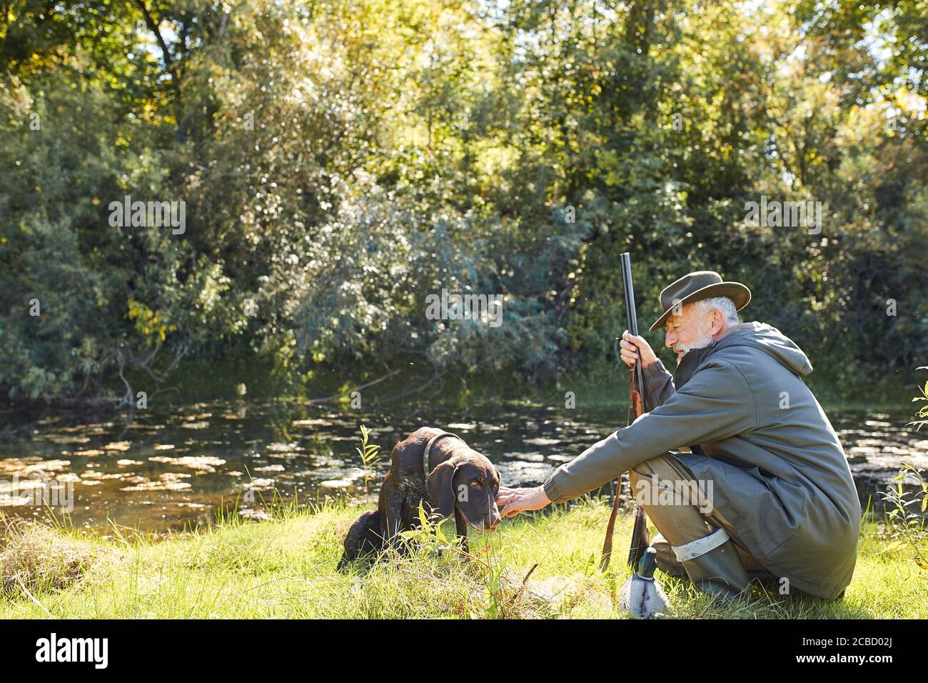 Have rest before hunting. Hunter man on lake, holding rifle Stock Photo ...