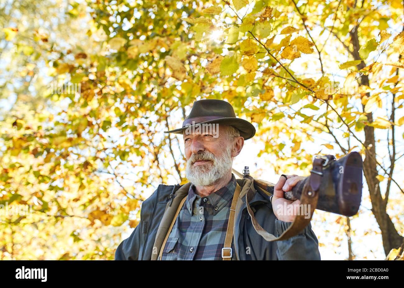 Satisfied hunter carry rifle gun on shoulder, looking at camera.Autumn ...