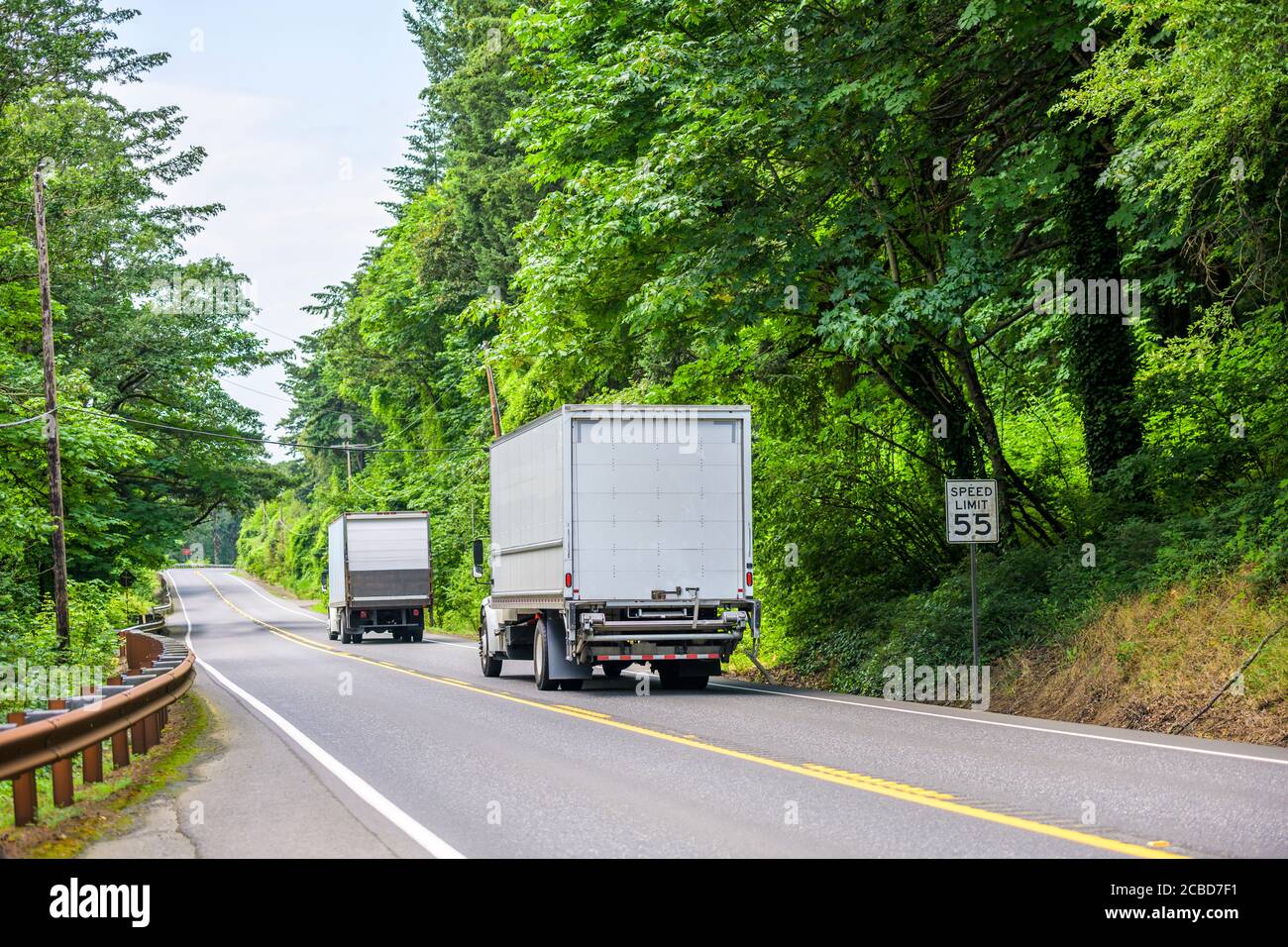 Two Loaded industrial big rig semi trucks with long box trailers ...