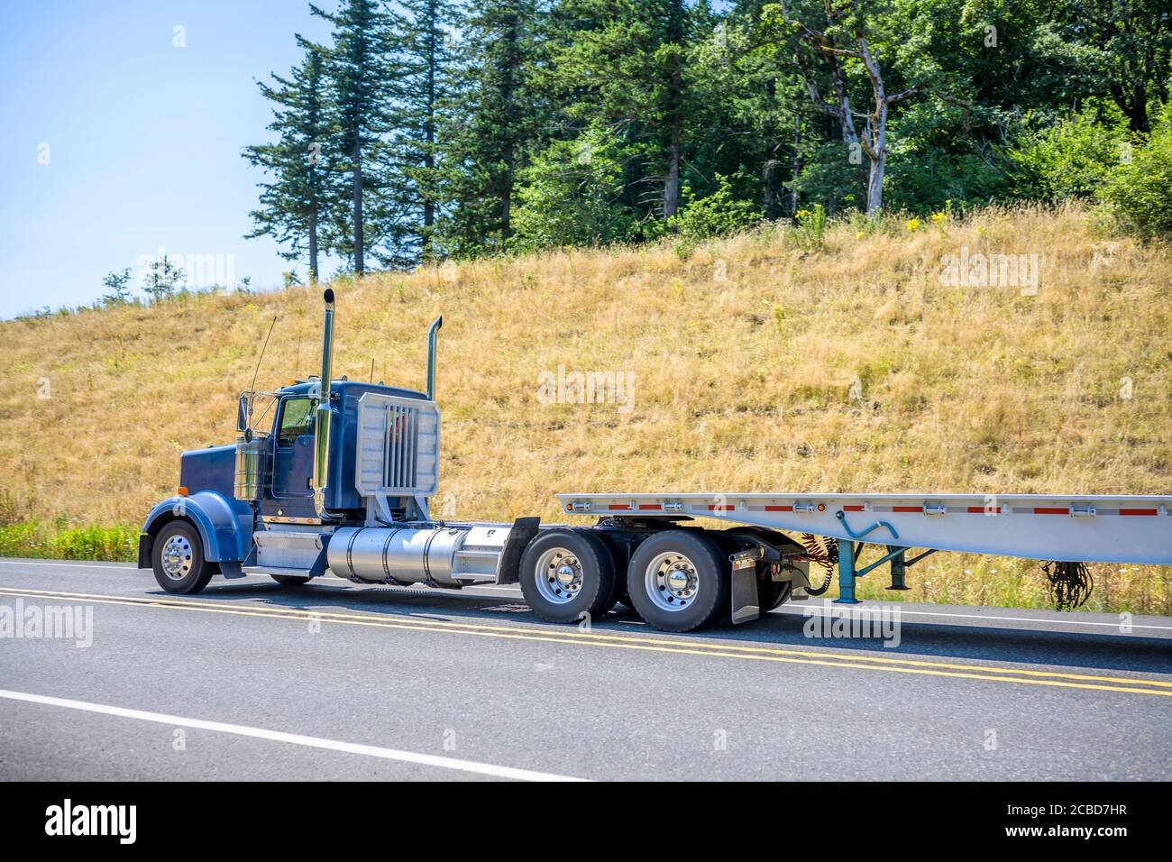 Blue classic big rig semi truck with day cab transporting empty semi ...