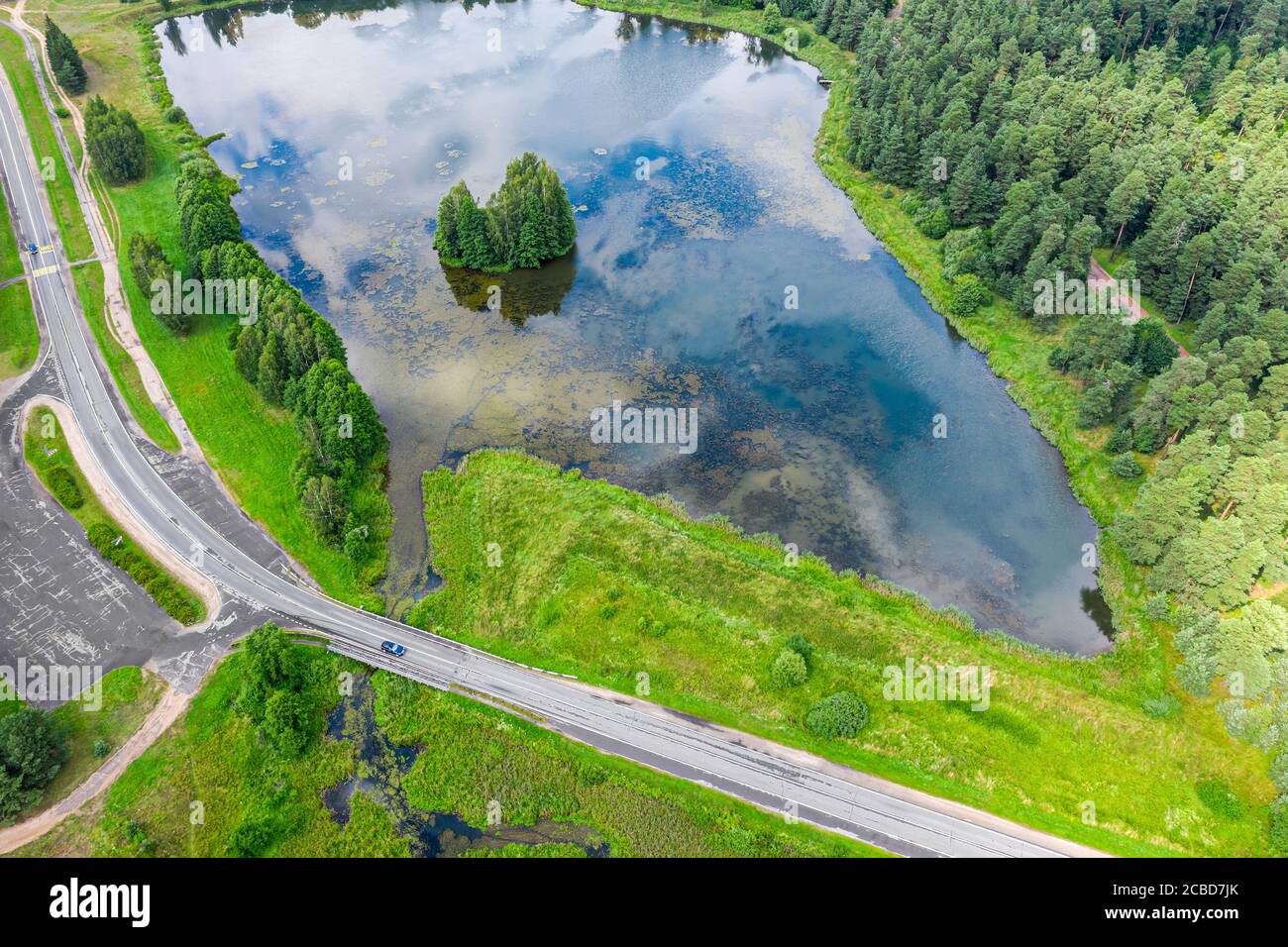 aerial view of small pond between green forest and country road. drone ...