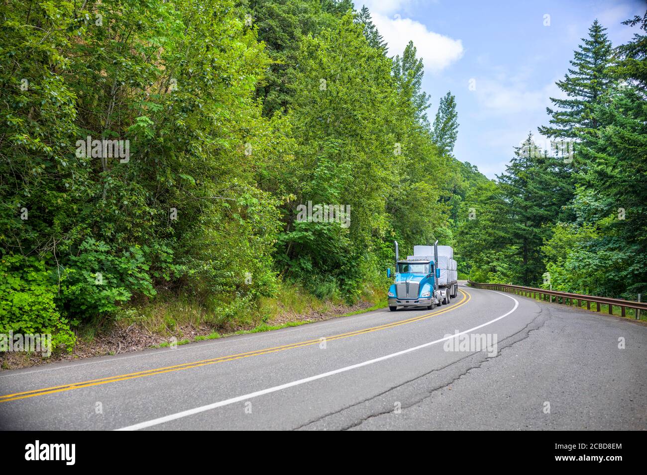 Blue classic day cab big rig semi truck transporting heavy loaded semi ...