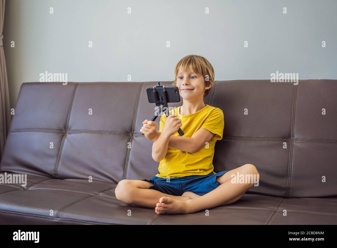 Staying connected. Happy young boy looking at his mobile phone and ...