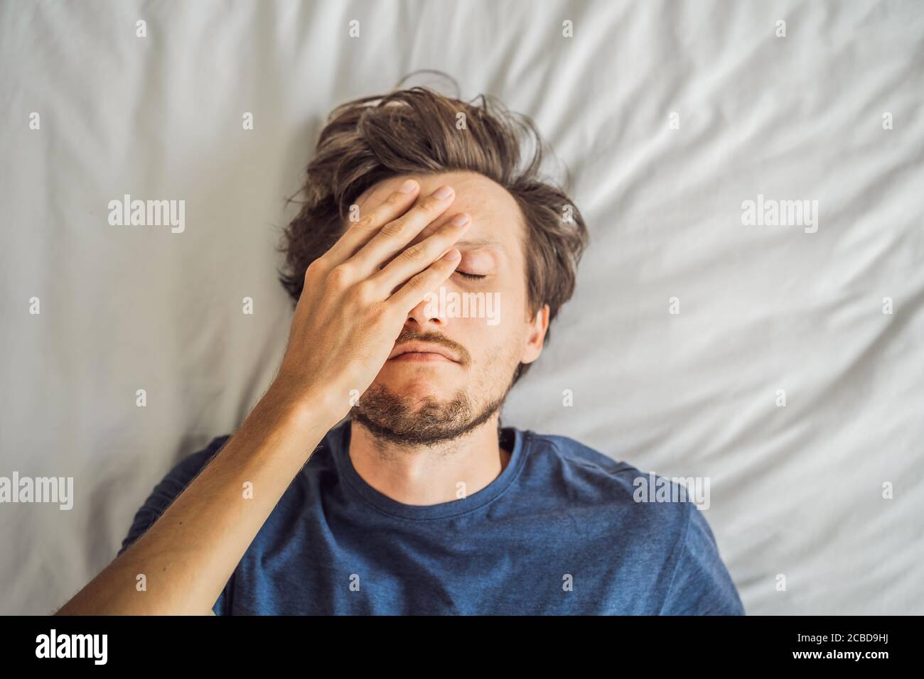 Extremly tired young man lying on the bed, home alone. self-isolation ...
