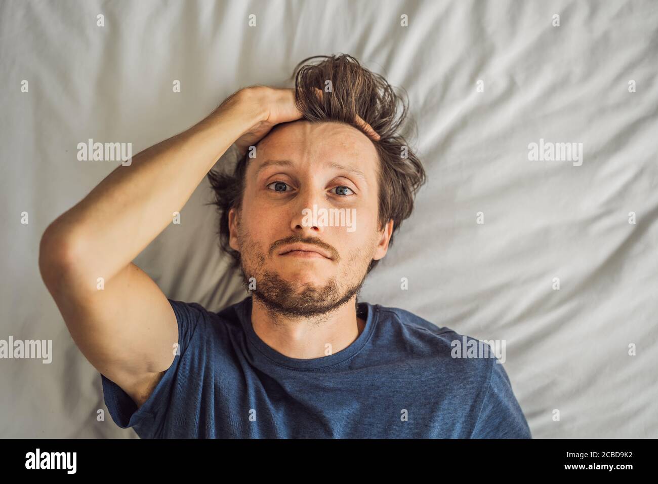 Extremly tired young man lying on the bed, home alone. self-isolation ...