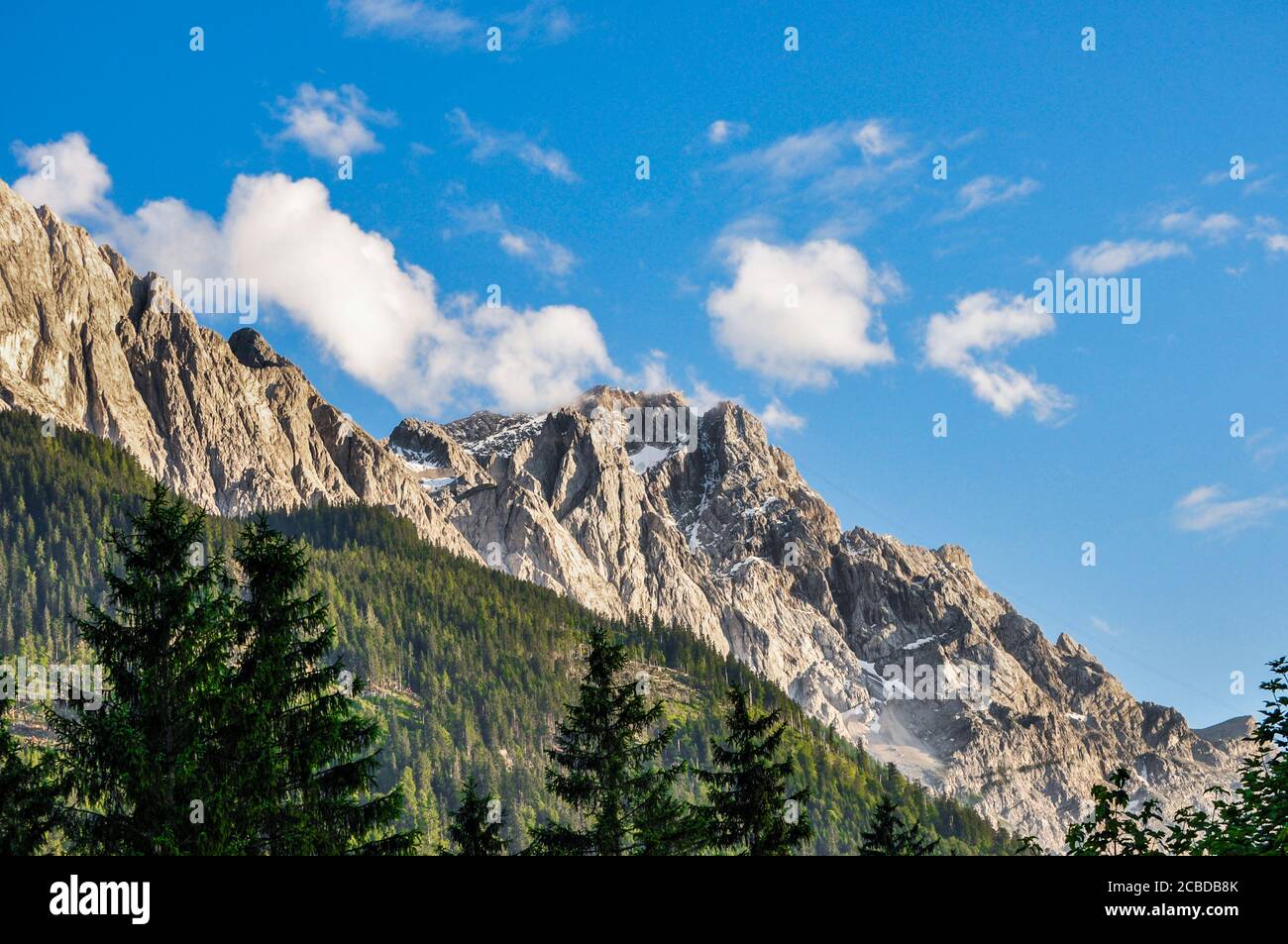zugspitze mountain in the summer, with green trees and blue sky Stock ...