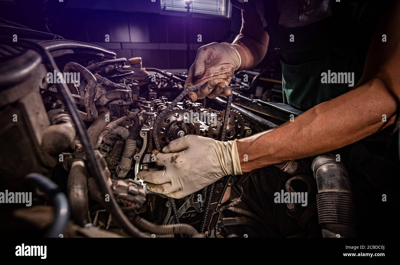 Car mechanic in garage with car engine after remove the cover part ...