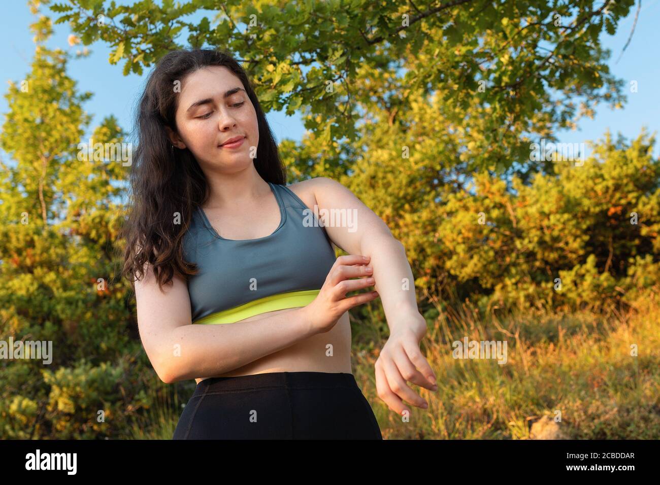 A young athletic woman scratches her hand from an insect bite during ...