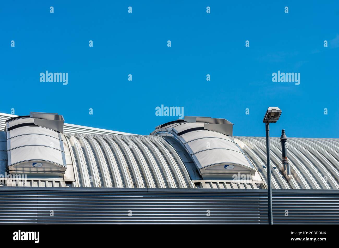 Curved roofing of an industrial building against a clear blue sky Stock ...