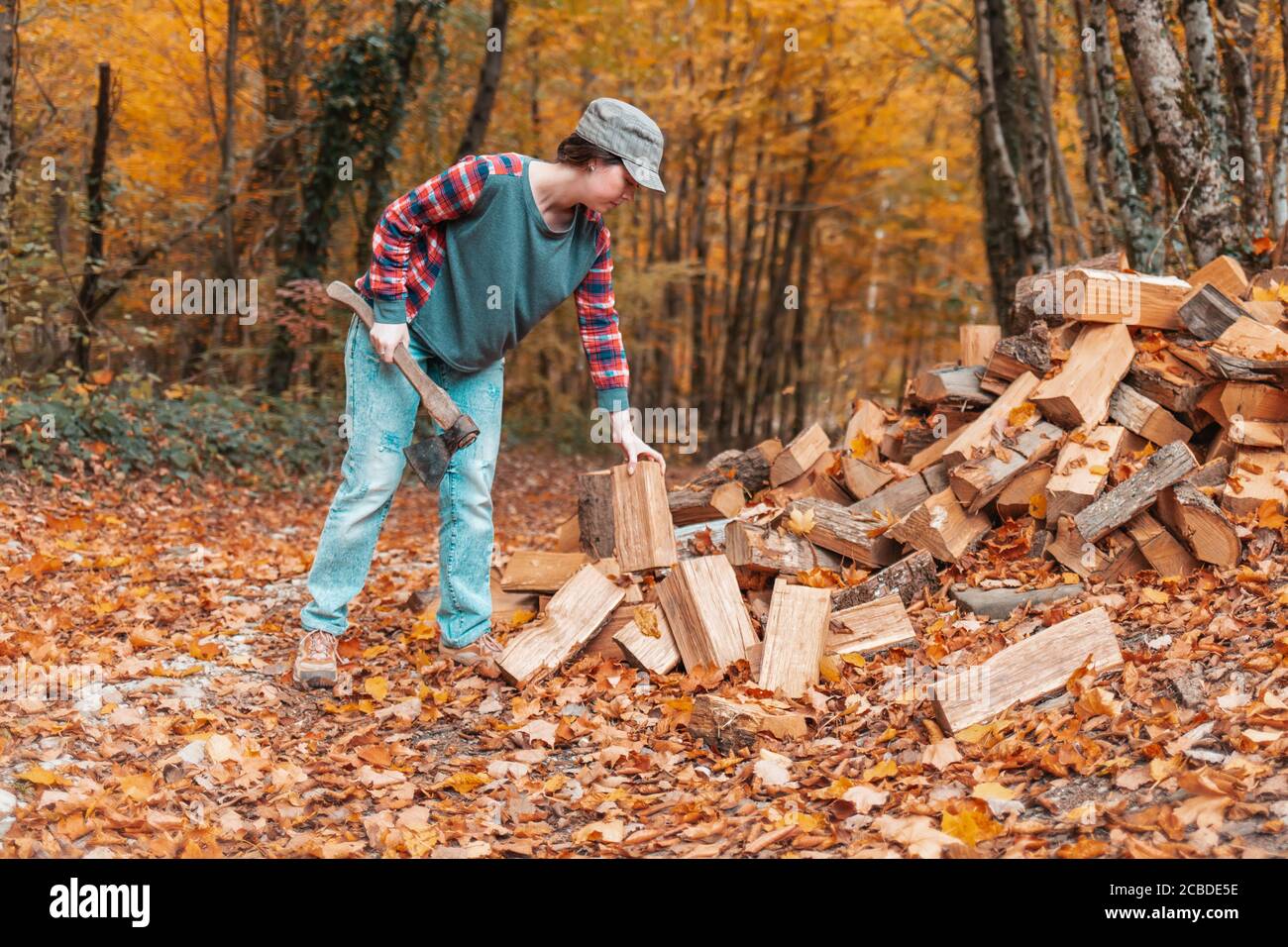 Preparation for the heating season. Young woman chopping wood. In the ...