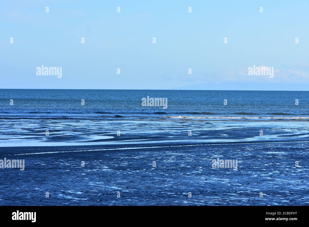 Shallow ocean coast with thin layer of water on sandy surface forming ...