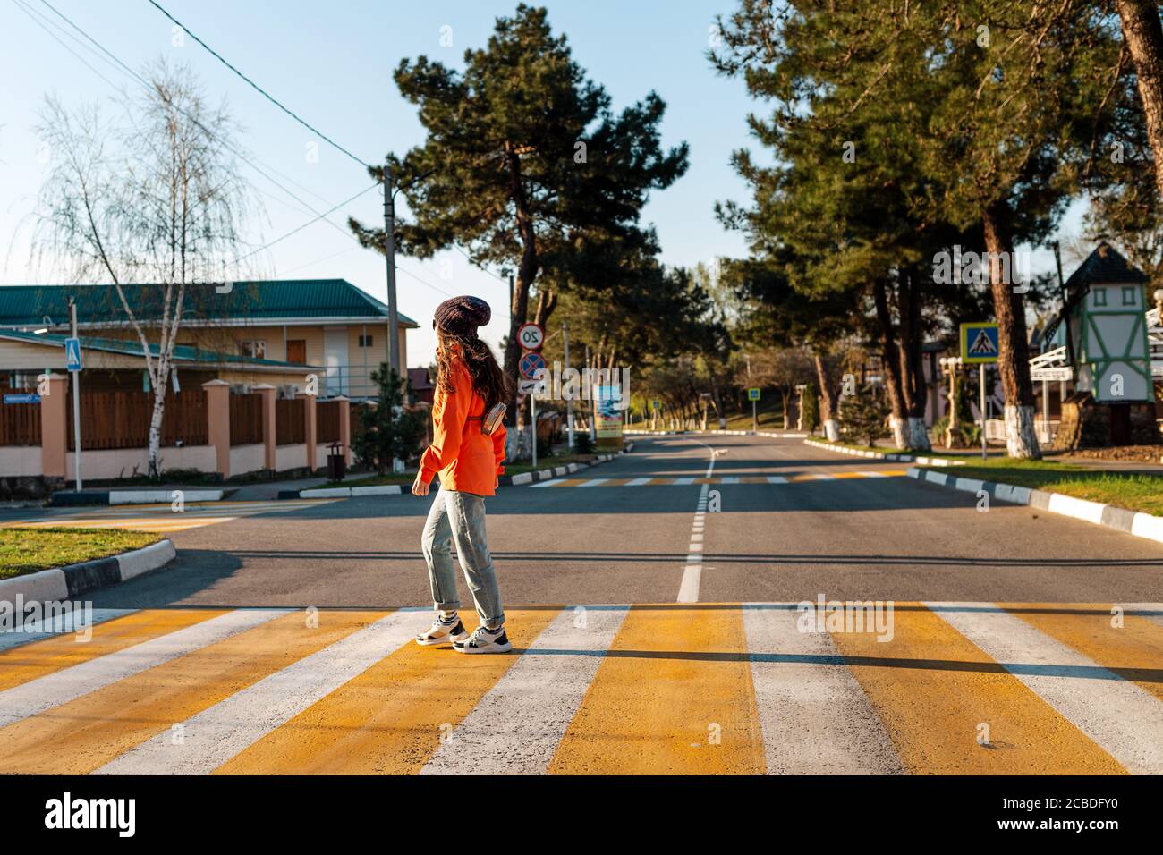 A young woman crosses a pedestrian crossing. Empty road and streets ...