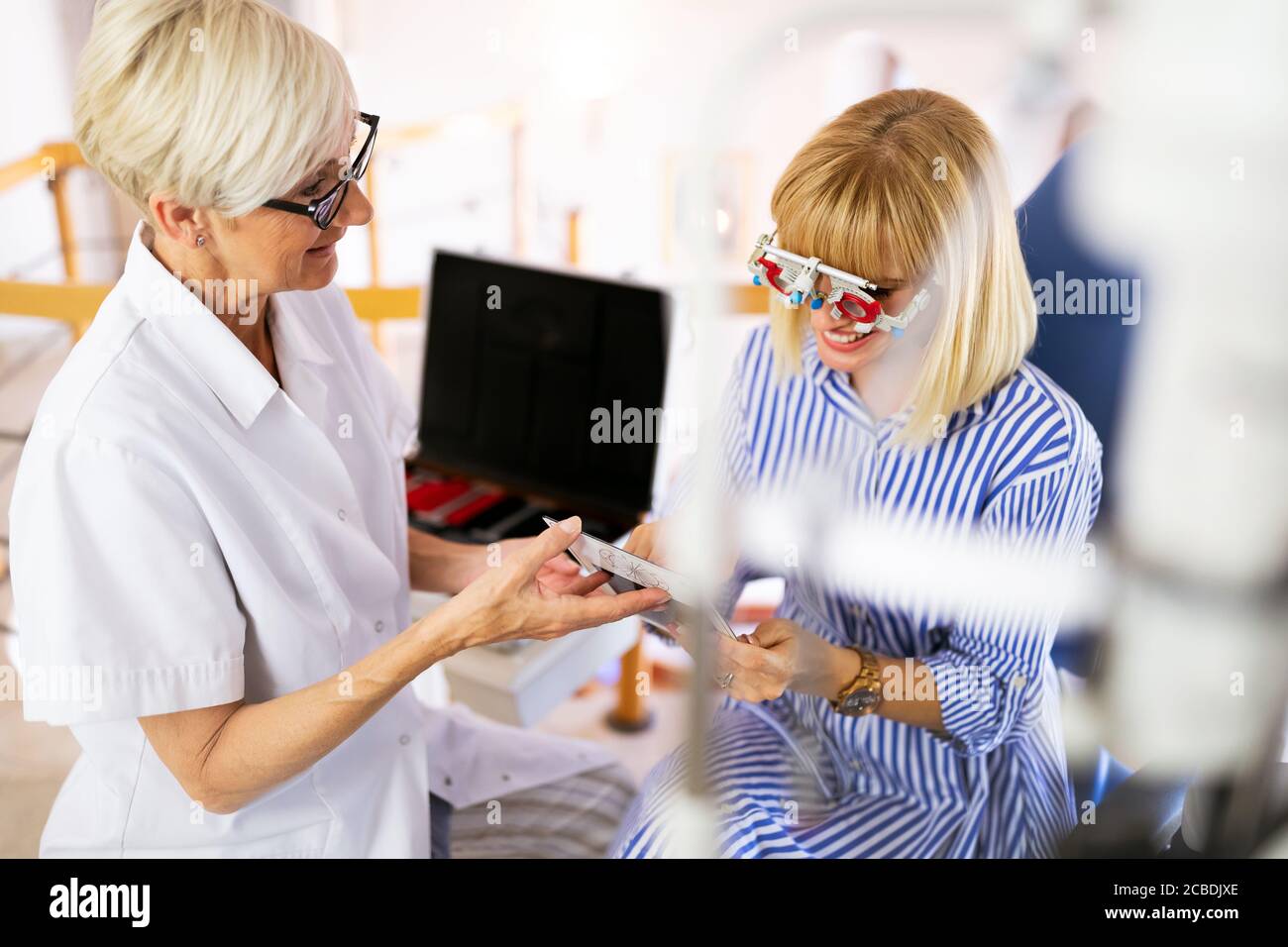 Senior woman optometrist examining patient in modern ophthalmology ...