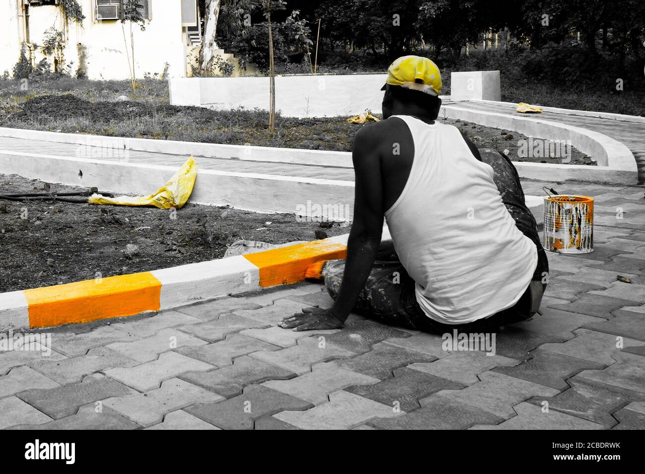 a man painting with yellow color on footpath in garden Stock Photo - Alamy