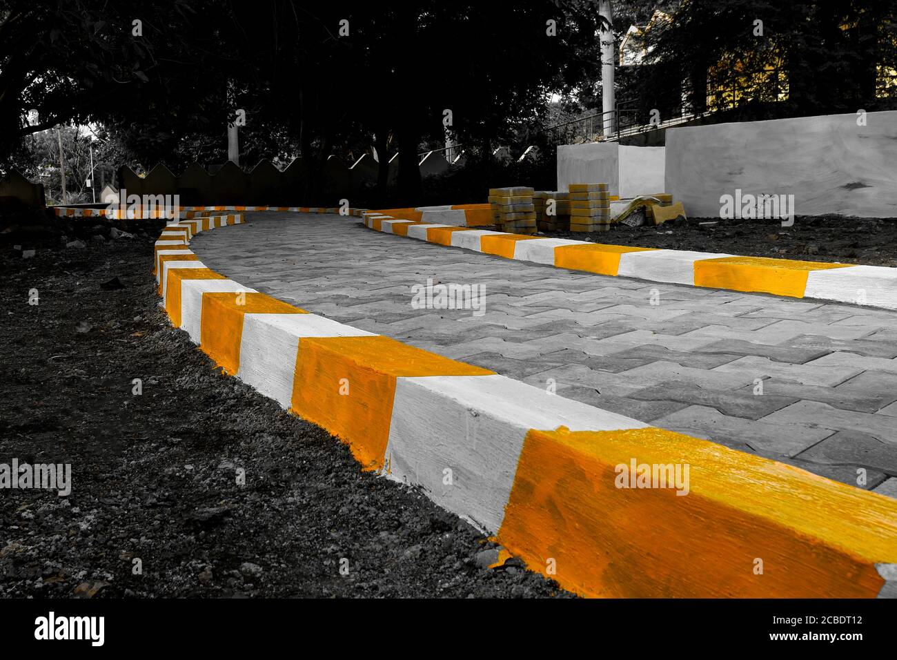 a long view of yellow & white color isolated on walking path in park ...