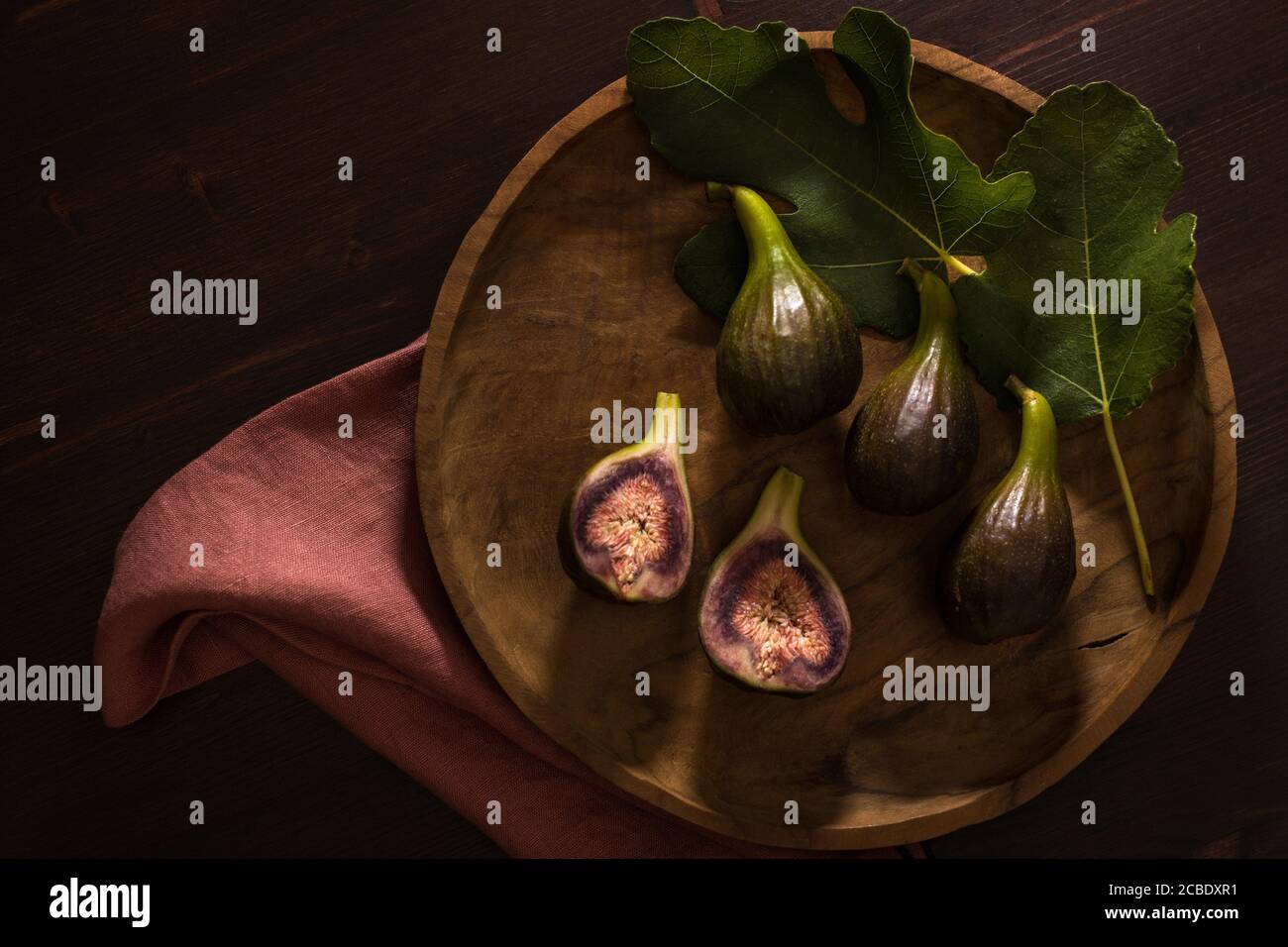 Juicy fresh whole fig fruits and one cut in half on round olive wood ...