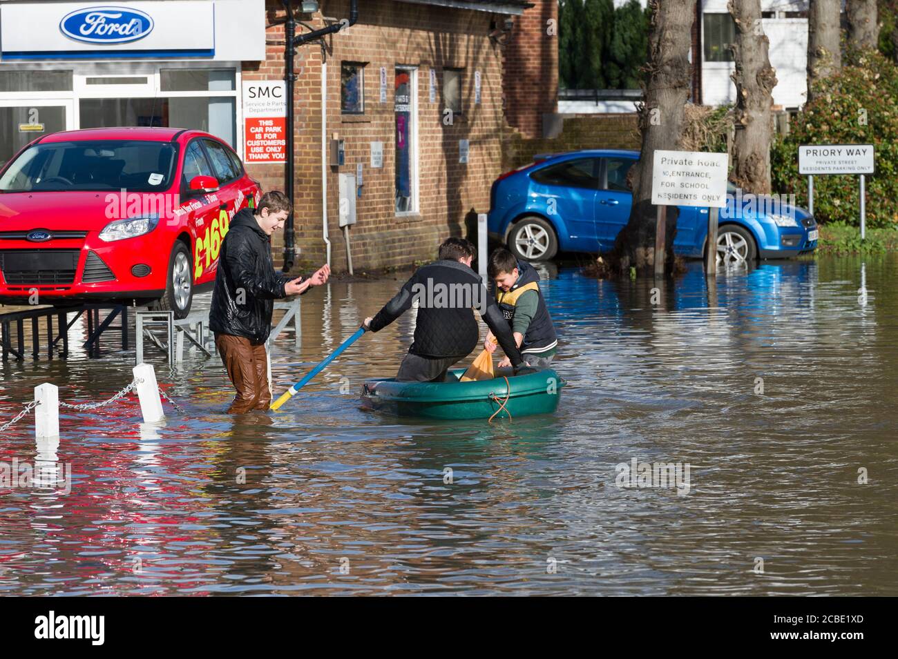 Boys peddling a boat through flooded Slough road in the village of ...